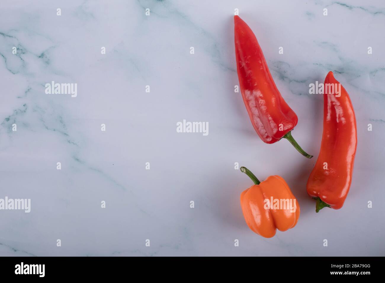Three chili peppers on a blue marble table Stock Photo - Alamy