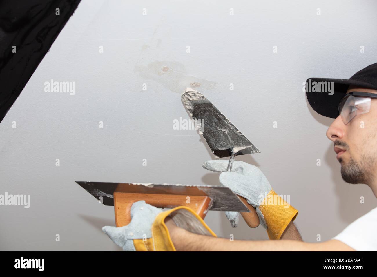 Closeup of a person covering the wall with plaster under the lights ...