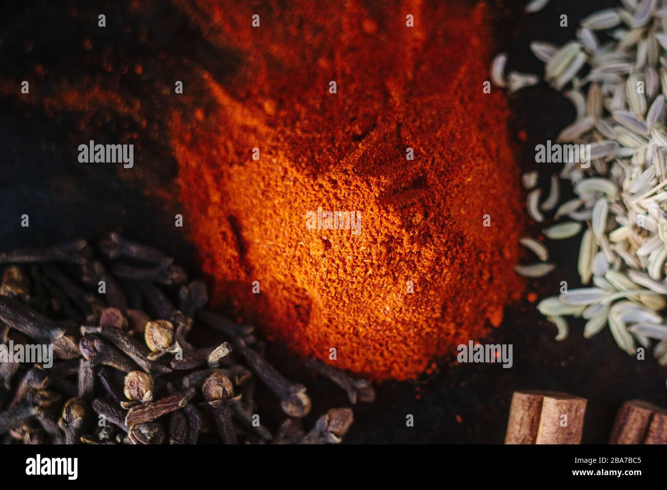 Grounded chili pepper on black rustic surface, surrounded by spices ...
