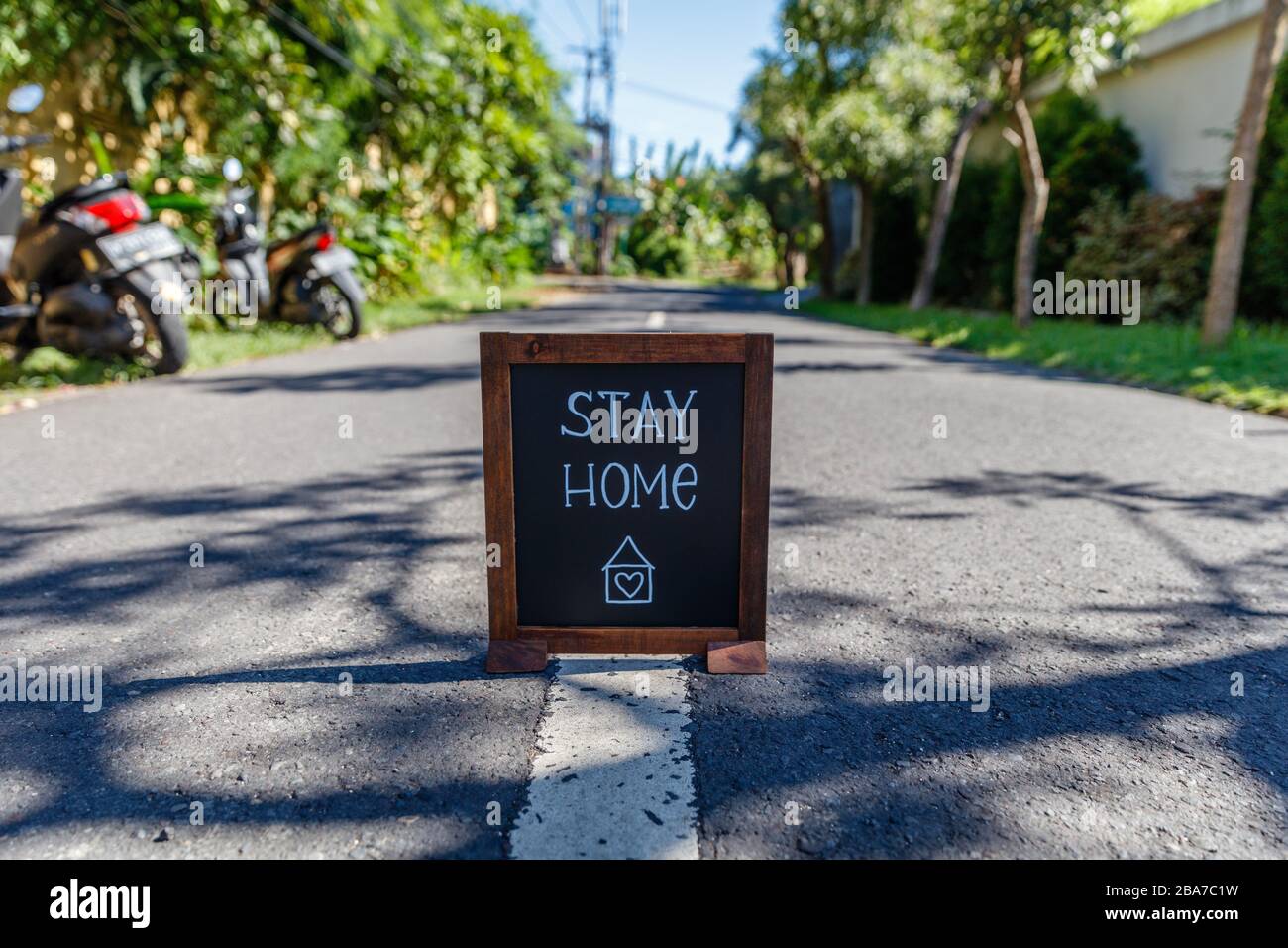 Black board sign STAY HOME standing in the empty street Stock Photo - Alamy