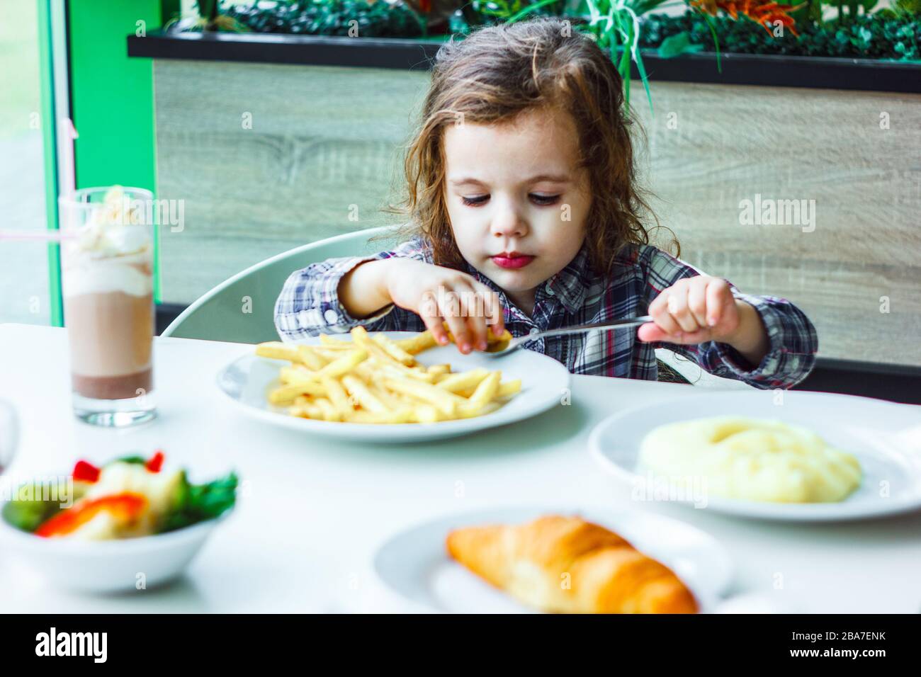 Little girl having lunch in the restaurant with the table knife and ...
