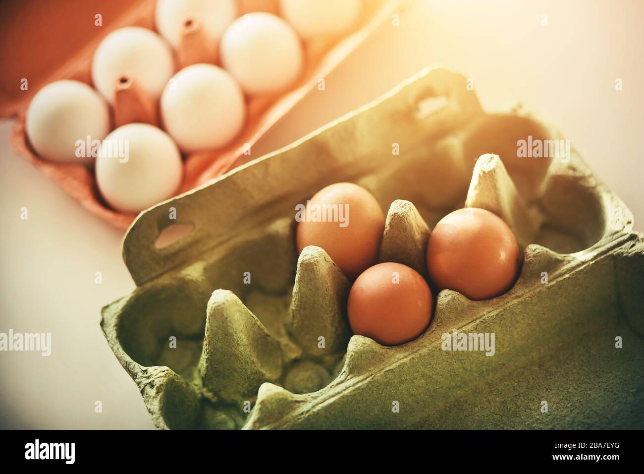 Raw eggs in white and brown shells lie in red and green cardboard ...