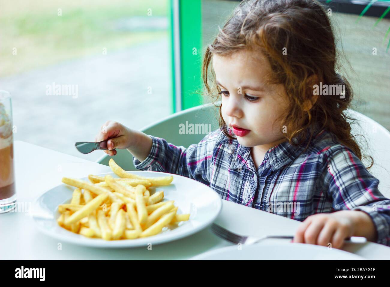 Little girl having lunch in the restaurant with the table knife and ...