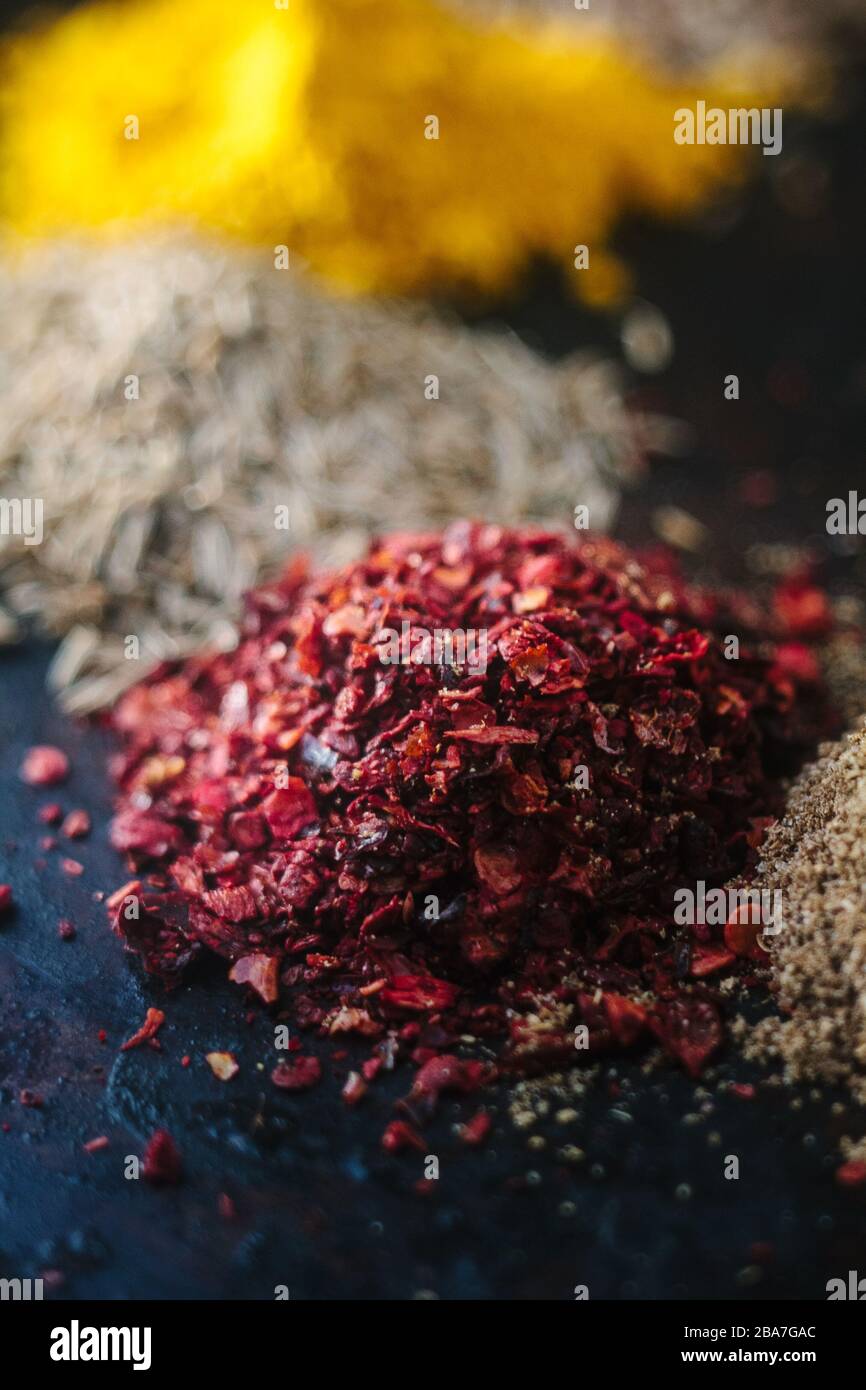 Red sumac spice on black metal plate surrounded by other spices Stock ...