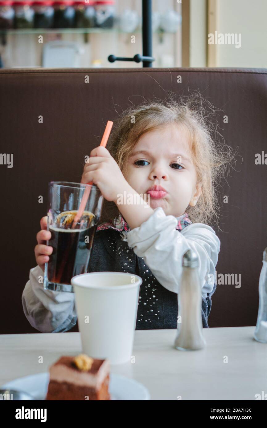 Adorable kid girl drinks cola in restaurant Stock Photo - Alamy