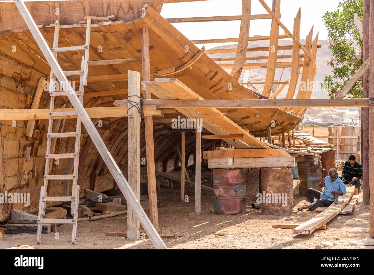 Traditional craftsmen work in a traditional Dhow boat building yard in ...