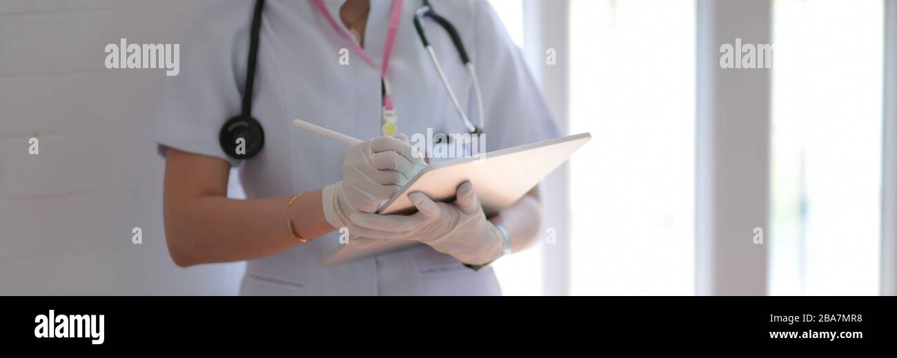 Side view of female doctor writing patient chart on digital tablet in ...