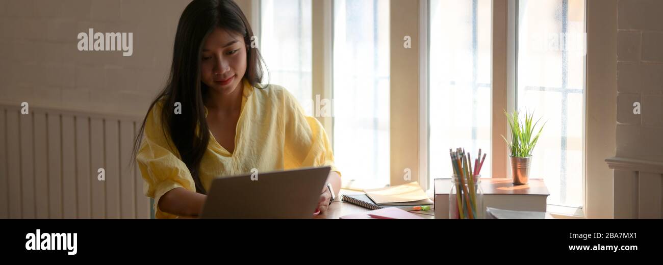 Cropped shot of university student focusing on her assignment with ...