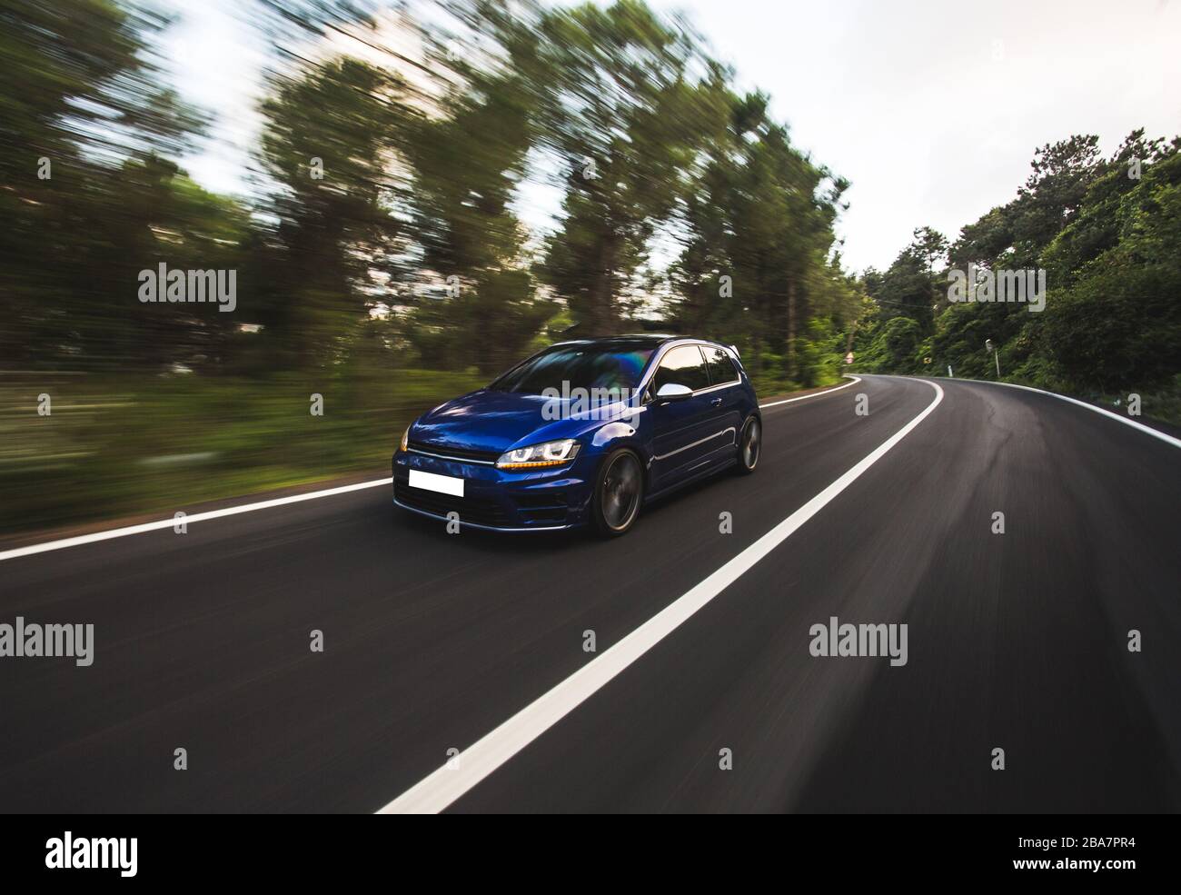 Blue business class hatchback commercial driving Stock Photo - Alamy