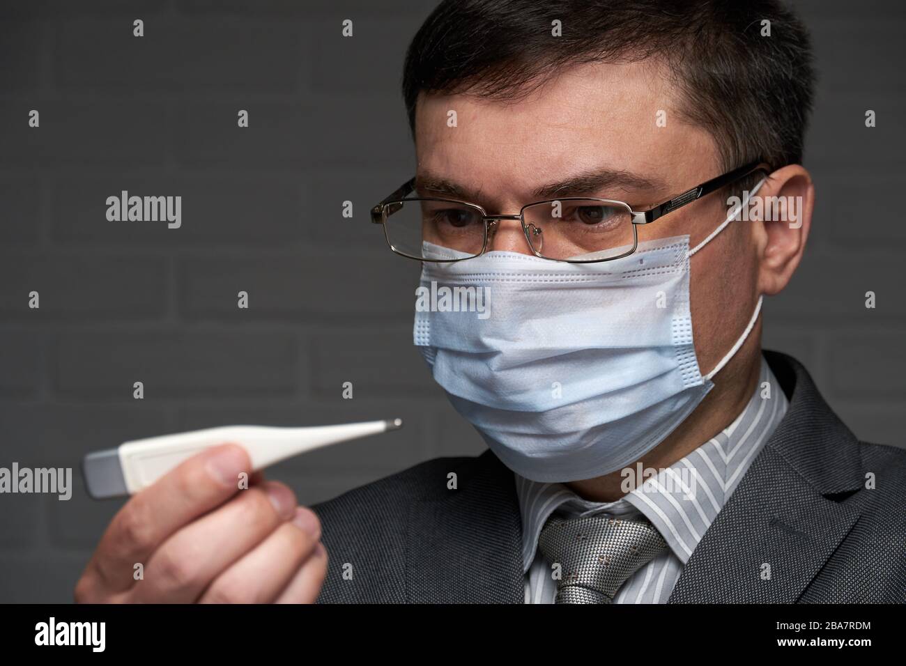 man measures body temperature with a thermometer, checks his health ...