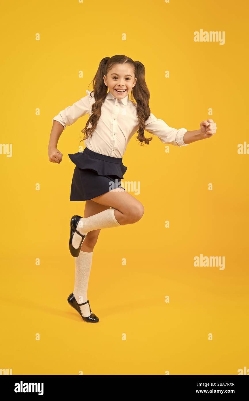 She is dynamic. Happy energetic schoolchild in motion on yellow ...