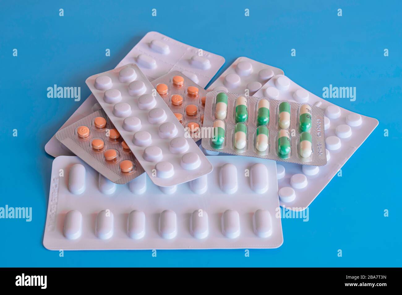 Seven blisters of generic tablets on blue background.Pills in packages ...
