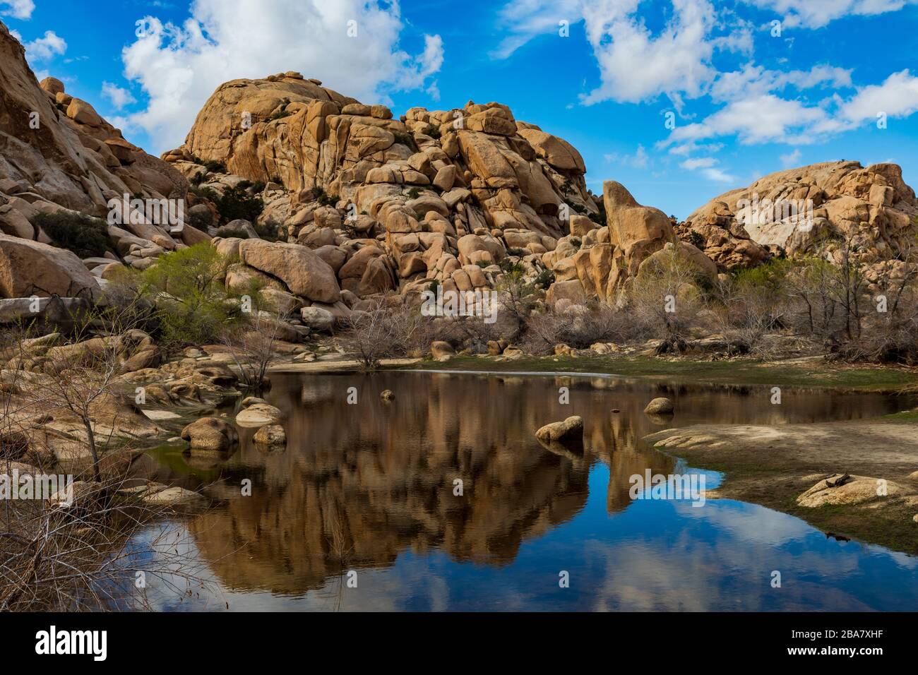 In this shot colorful rocks and boulders reflect in the still waters of ...