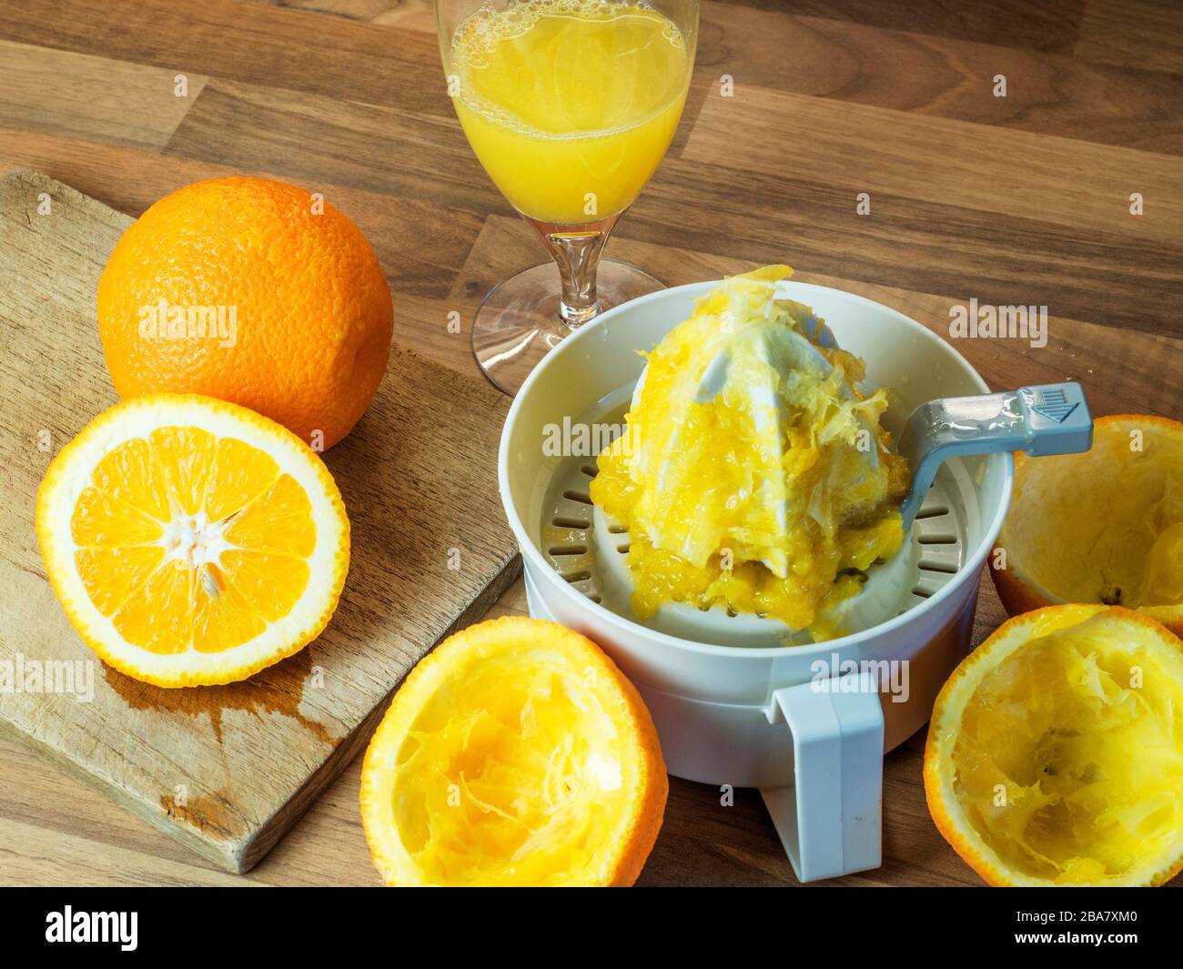Oranges and half orange on a chopping board with an orange squeezer and ...