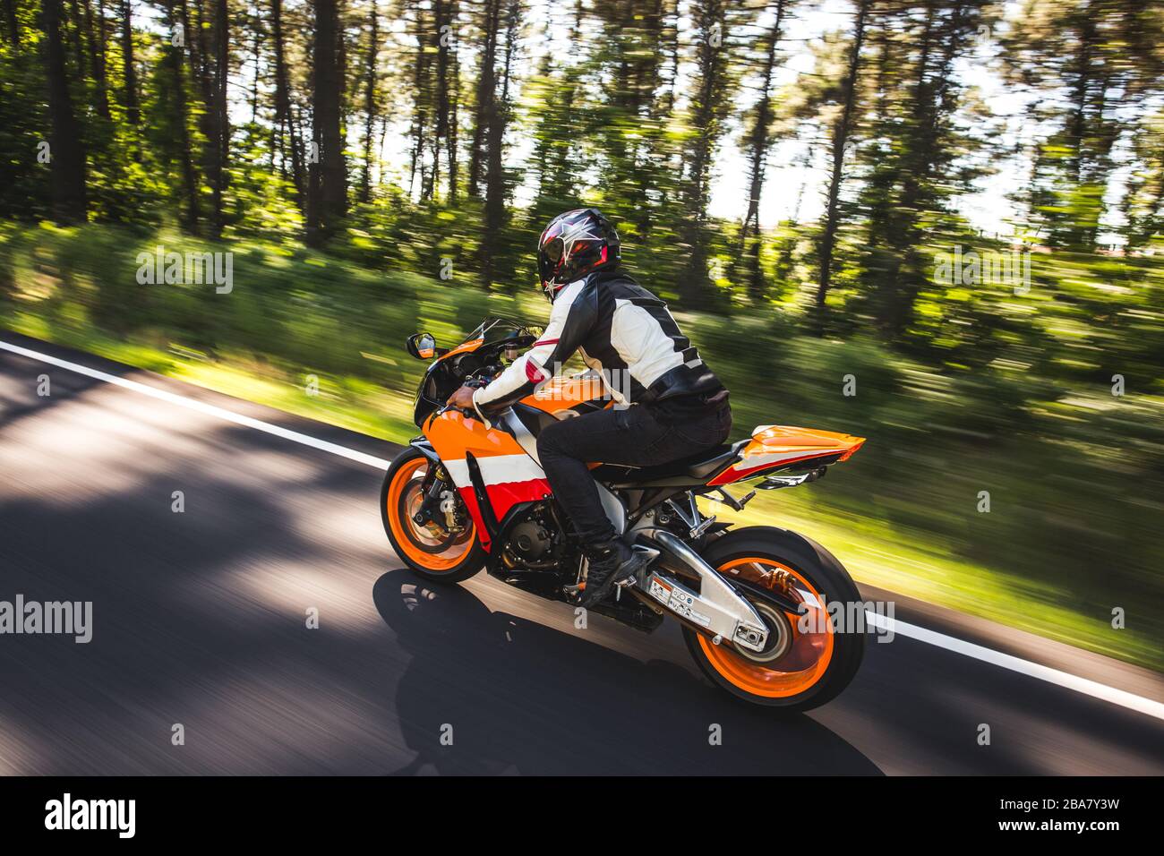 Orange color motorcycle with a driver in helmet and gear Stock Photo ...