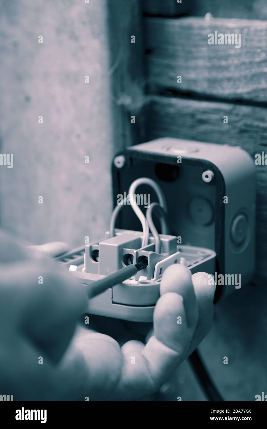 Man wiring an electric socket using an electrical screwdriver outdoor ...