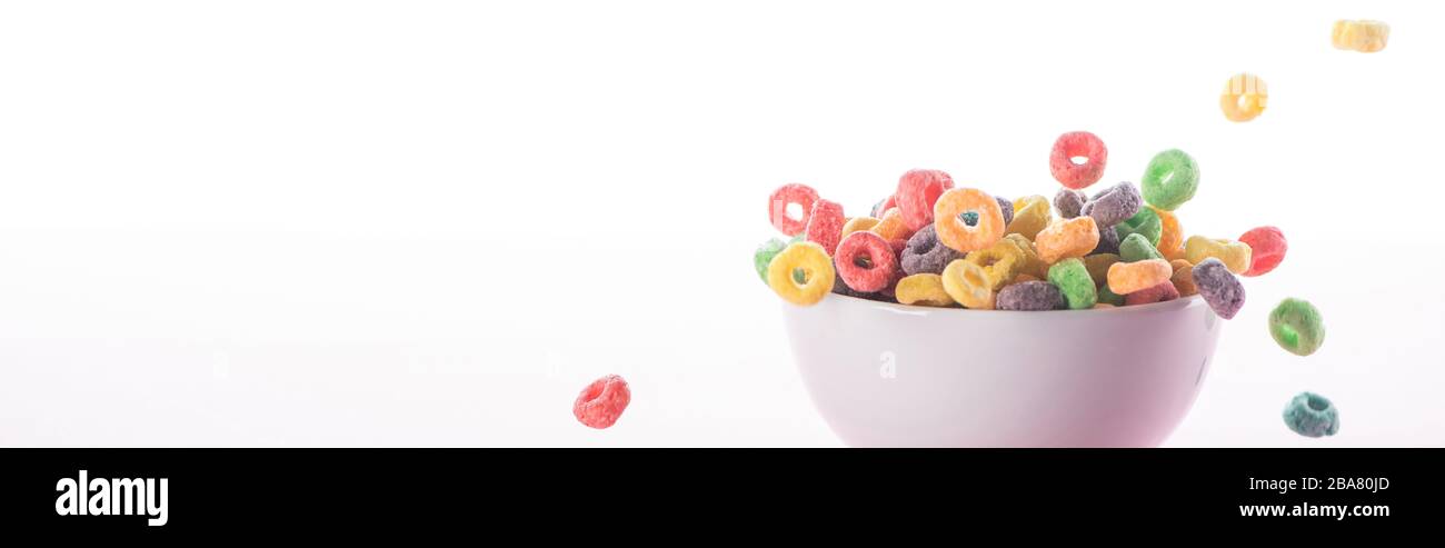 bright multicolored breakfast cereal falling in bowl isolated on white ...