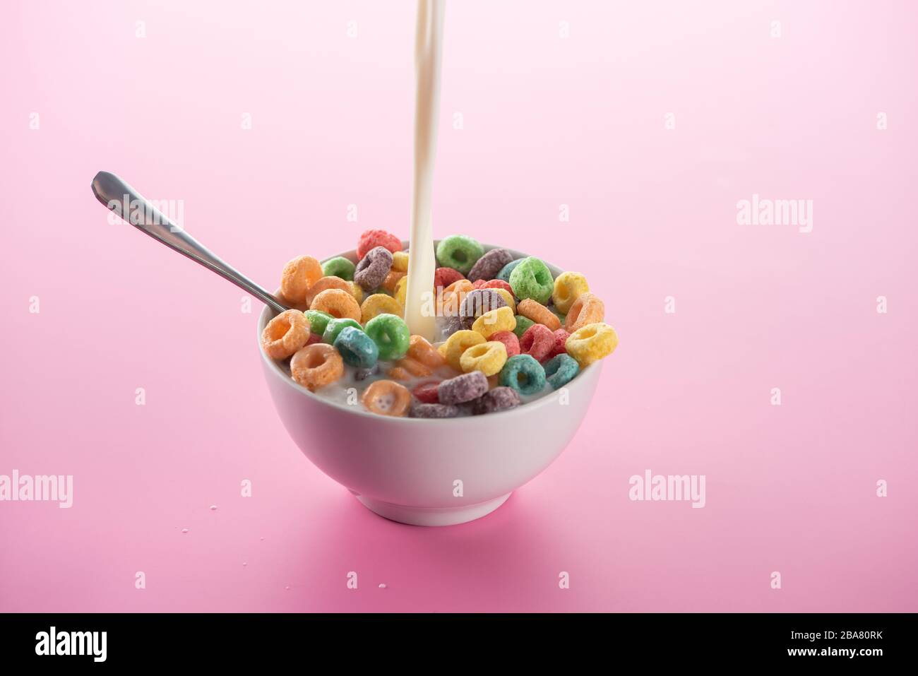 bright multicolored breakfast cereal in bowl with pouring milk and ...