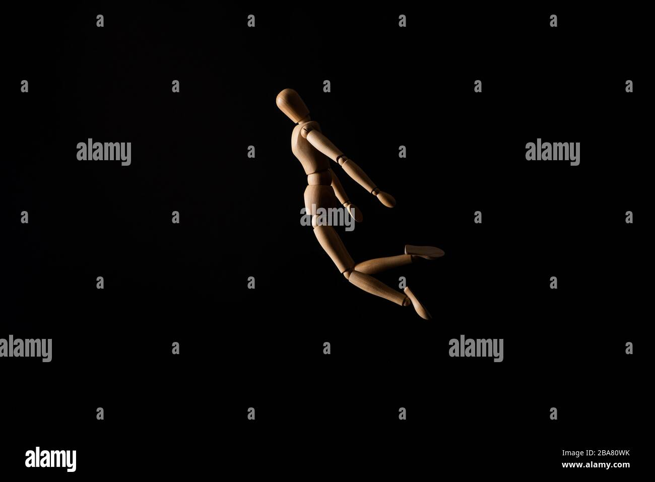 Wooden doll in falling position on black background Stock Photo - Alamy