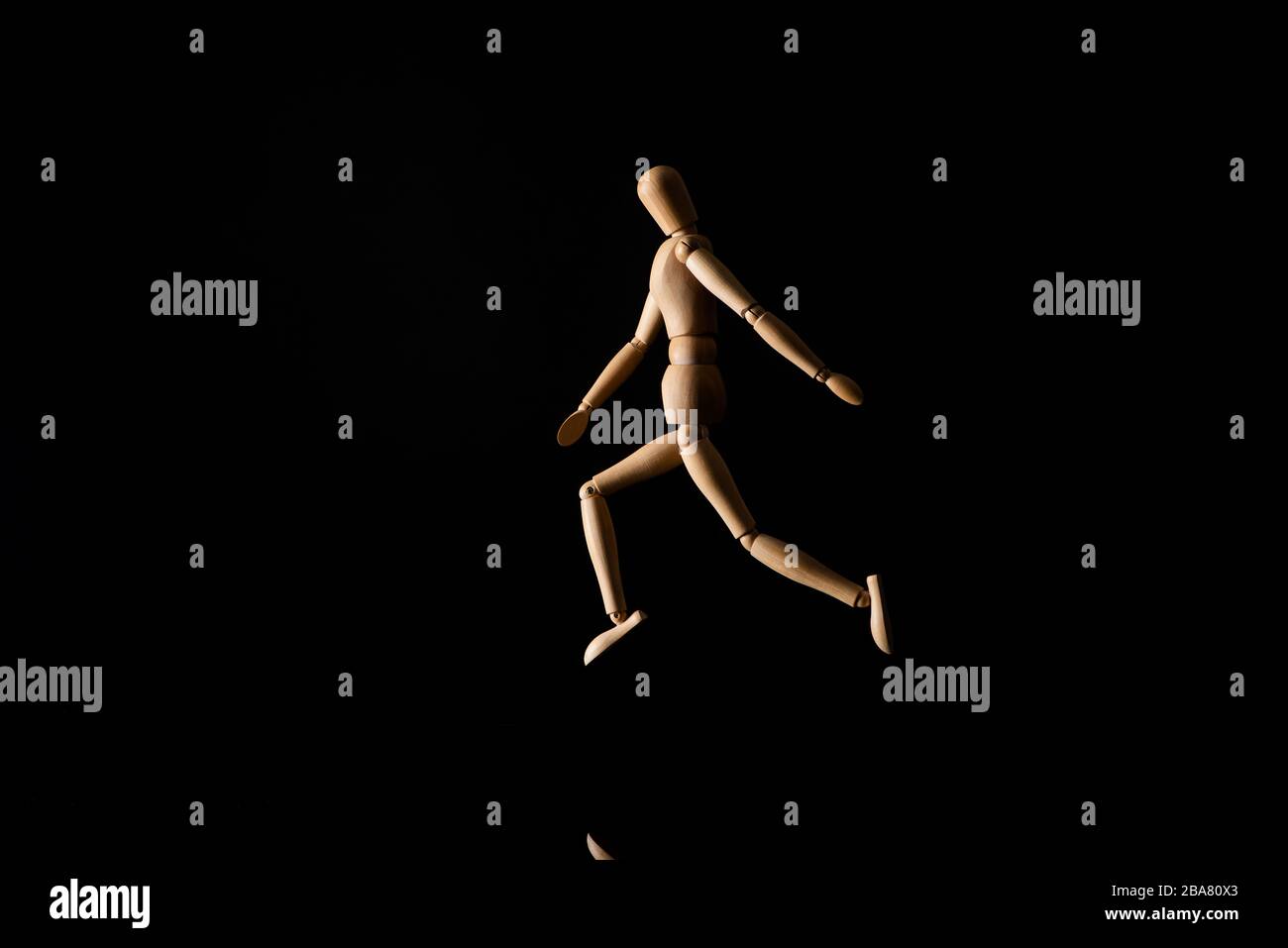 Wooden doll imitating running on black Stock Photo - Alamy