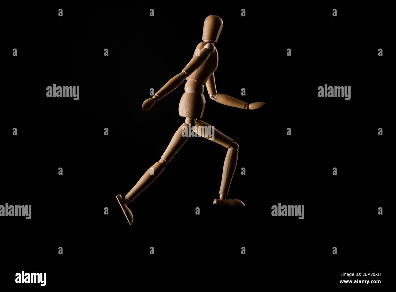 Wooden doll imitating running isolated on black Stock Photo - Alamy