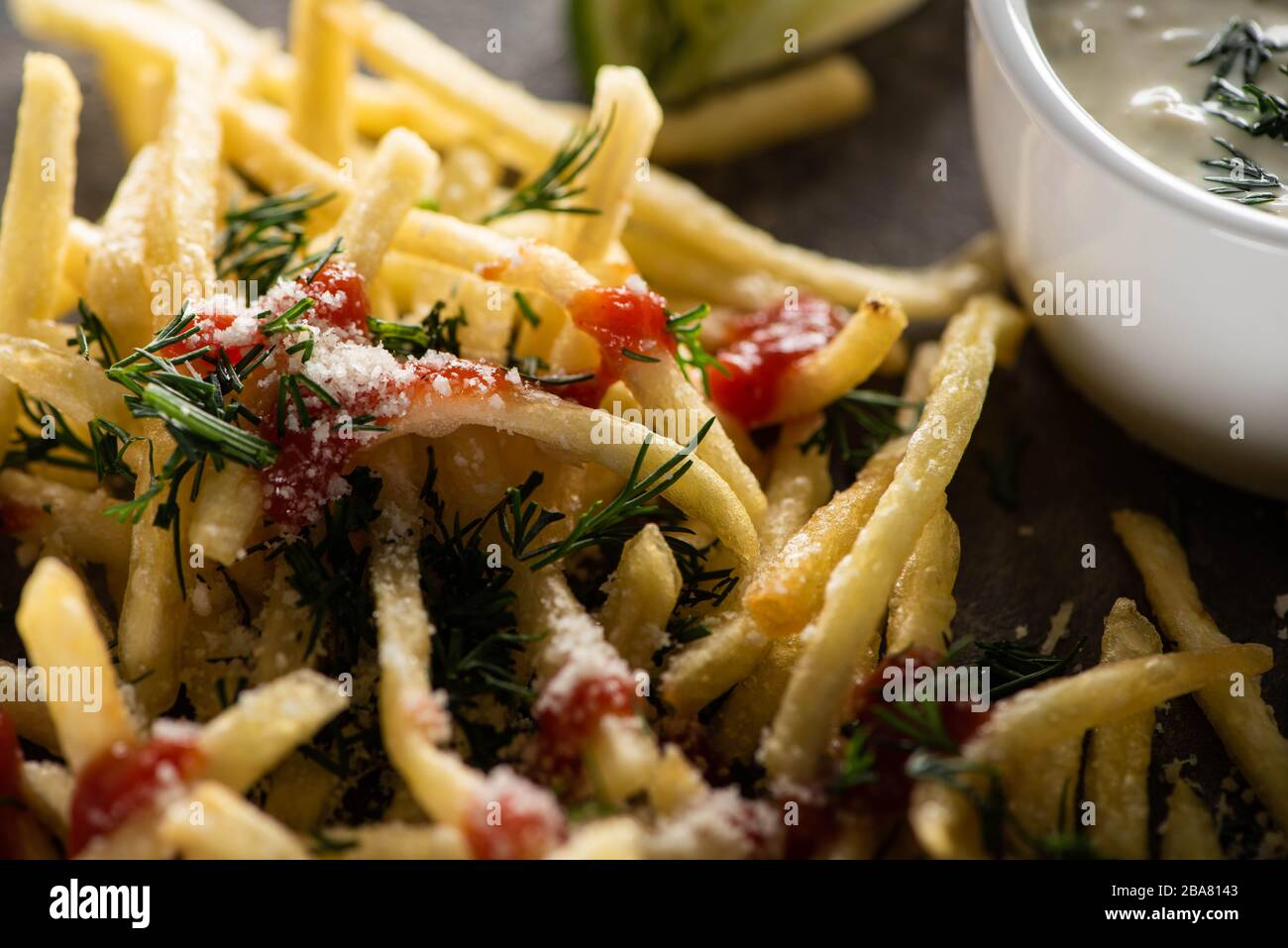 close up of tasty french fries with ketchup, salt and dill near garlic ...