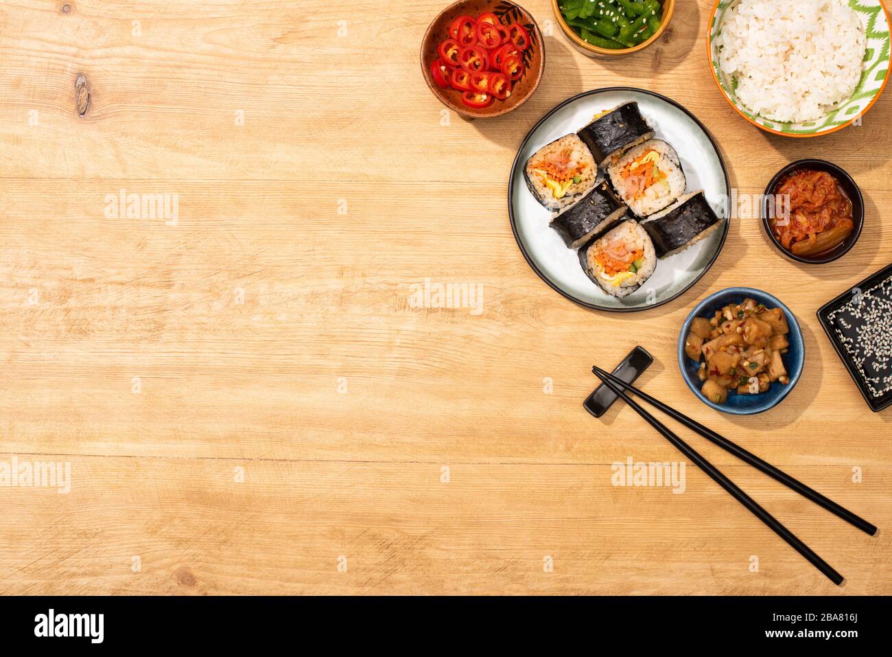 top view of bowls with tasty korean side dishes near chopsticks and ...
