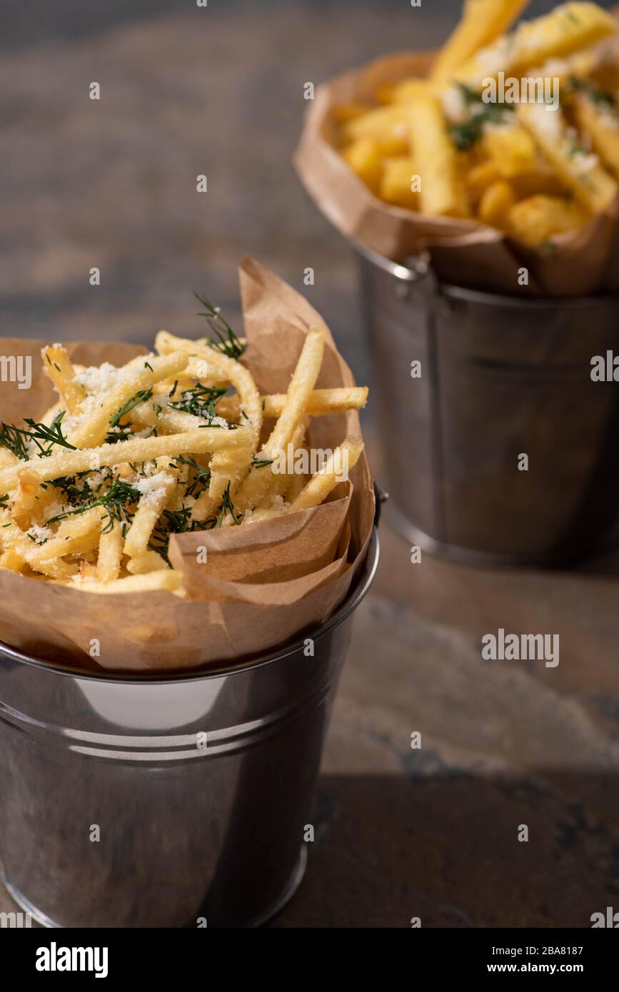 selective focus of bucket with crispy french fries on marble surface ...
