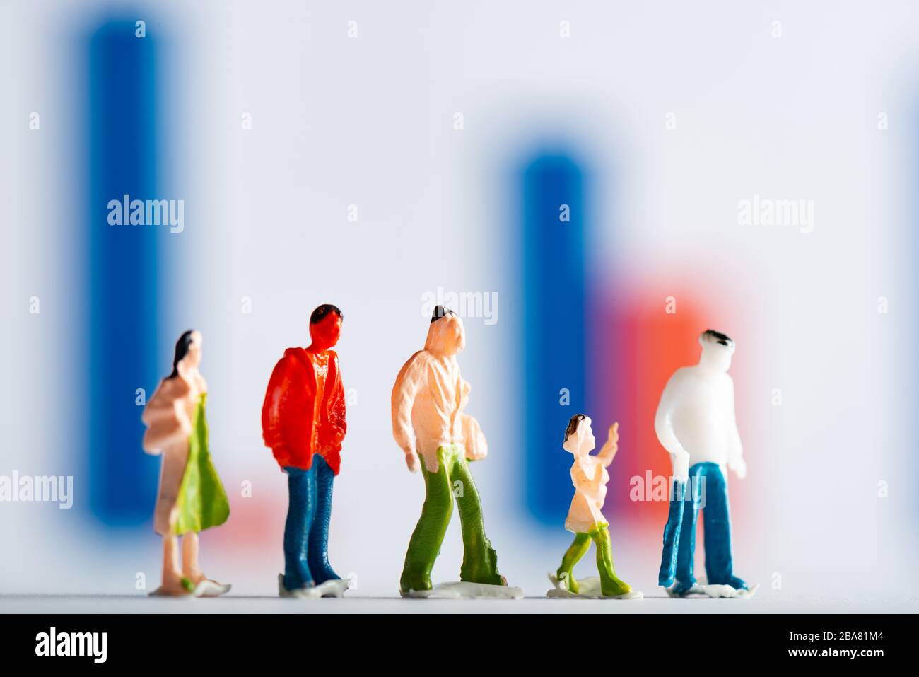 Selective focus of row of people figures on white surface with graphs ...