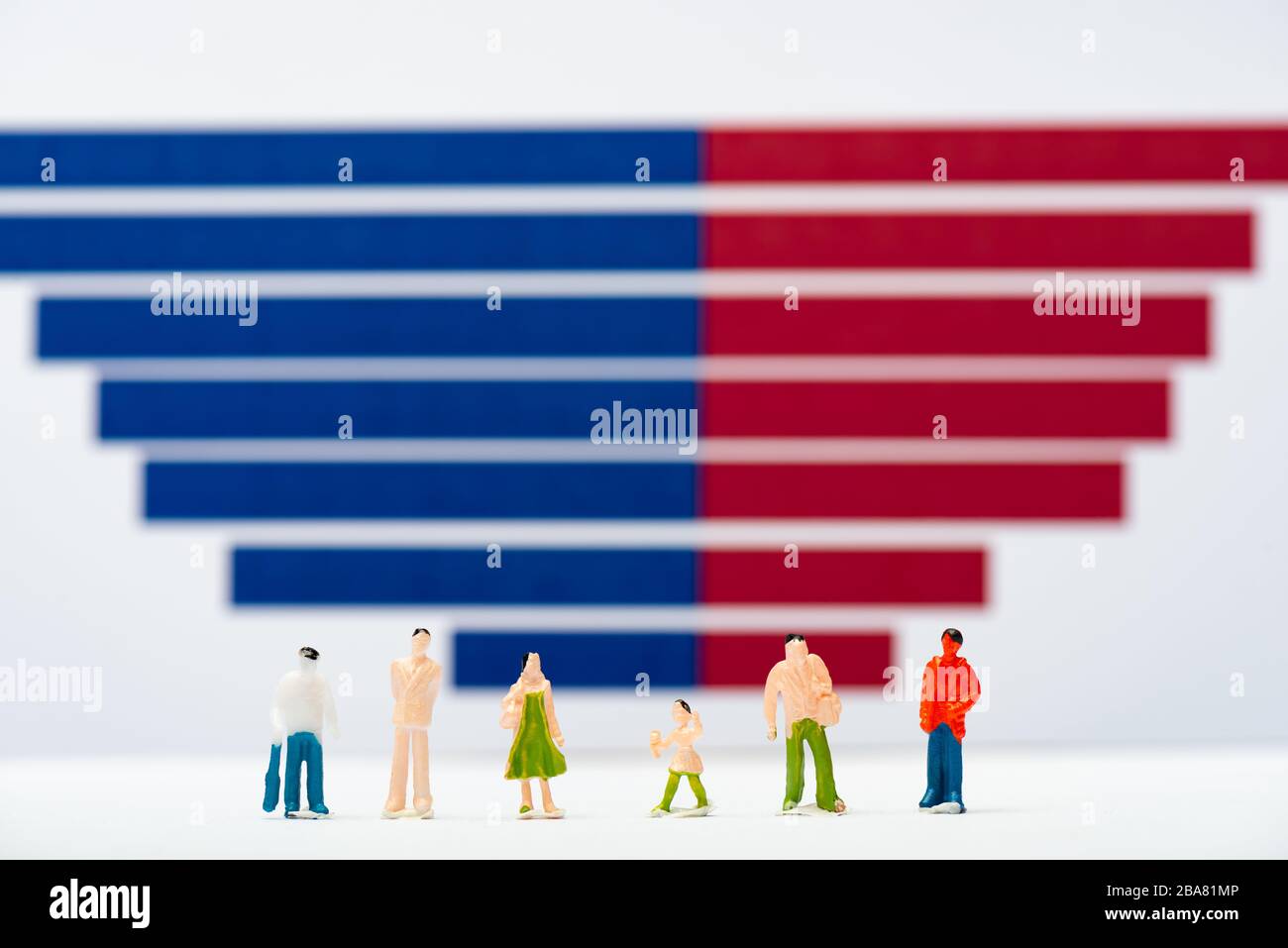 Selective focus of plastic people figures on white surface near blue ...