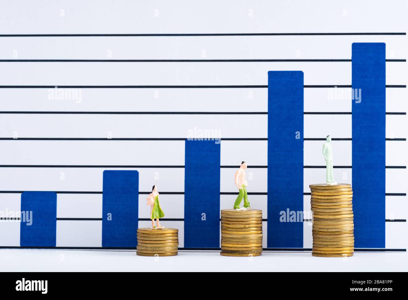Plastic people figures on stacked coins on white surface with blue ...