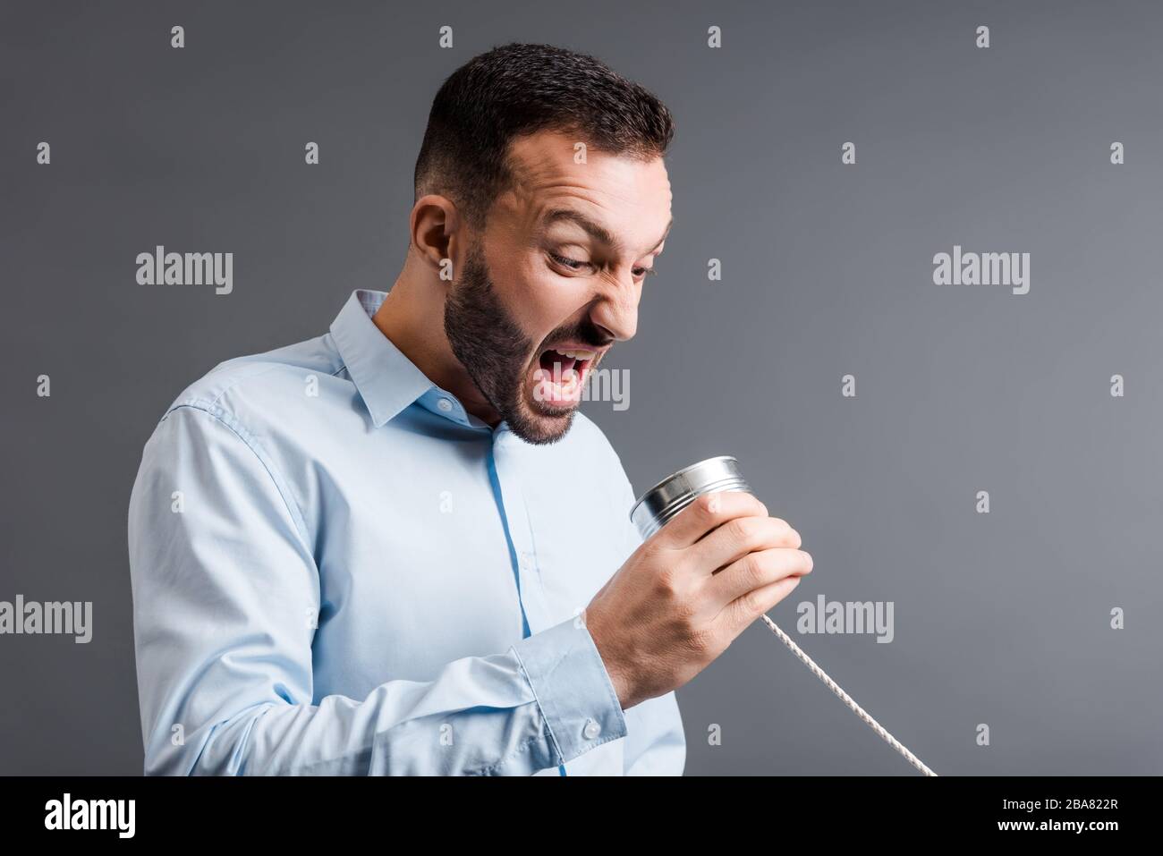 angry man screaming while holding tin can isolated on grey Stock Photo ...