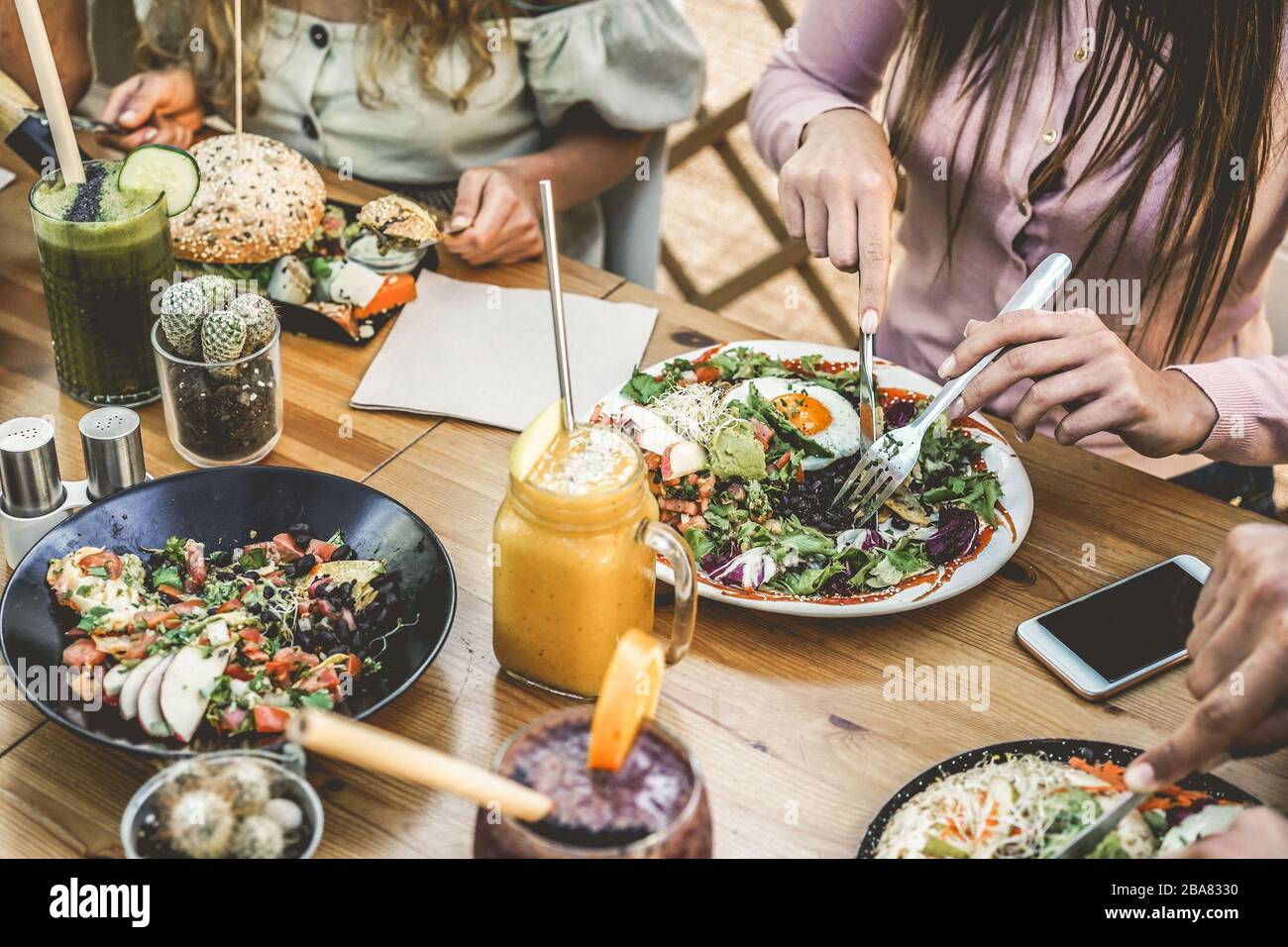 Hands view of young people eating brunch and drinking smoothies bowl ...