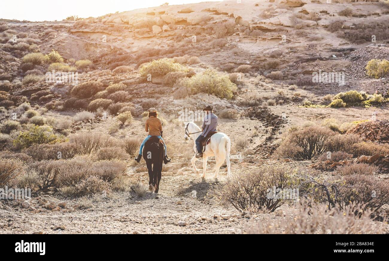 Young people riding horses doing excursion at sunset - Wild couple ...