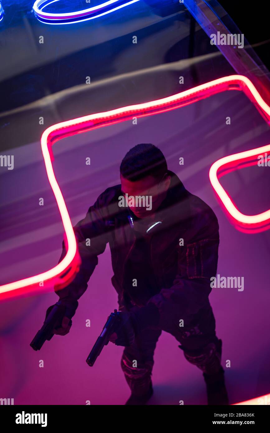 overhead view of armed mixed race cyberpunk player holding guns near ...