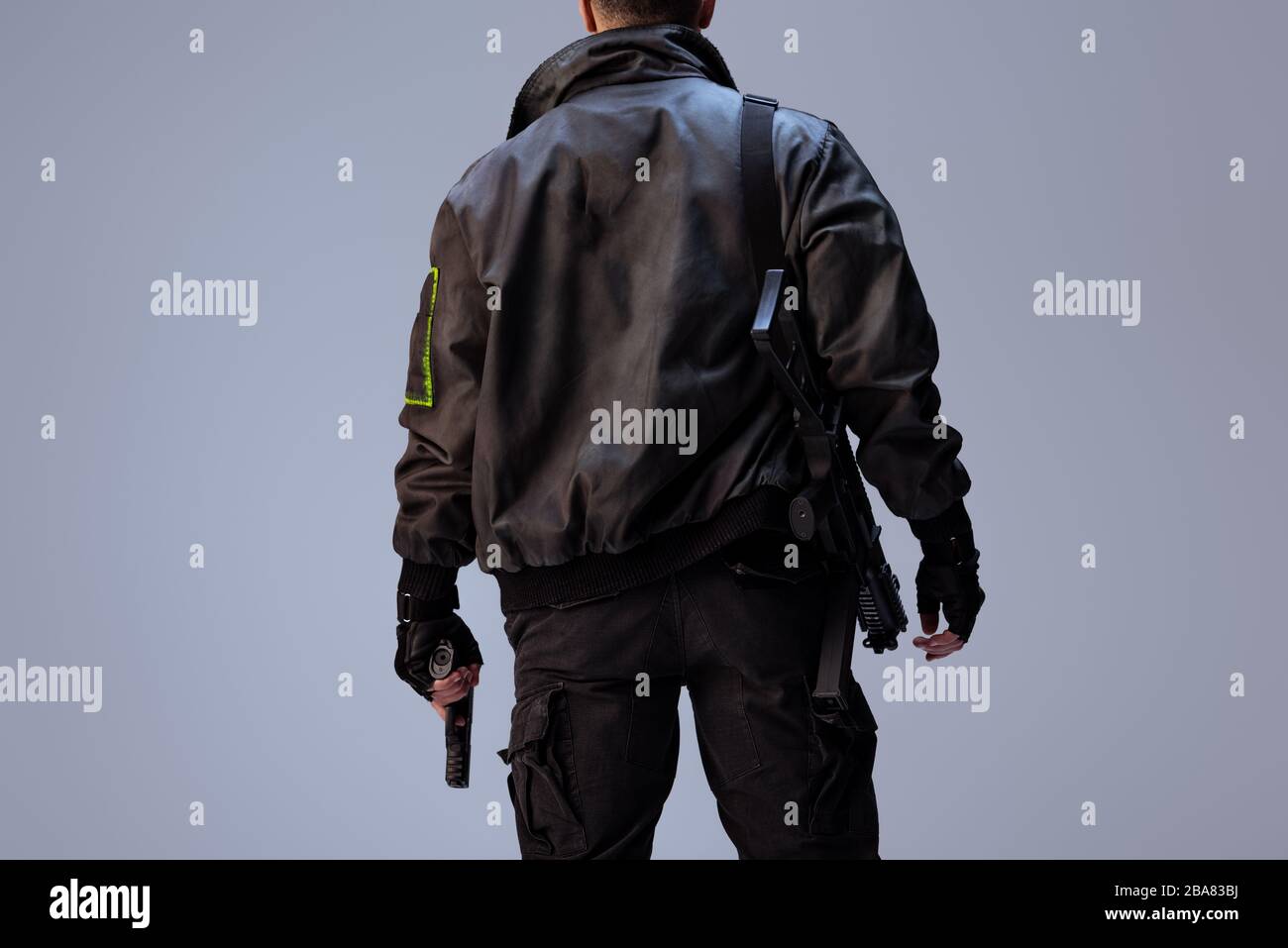 back view of cyberpunk player holding gun while standing isolated on ...