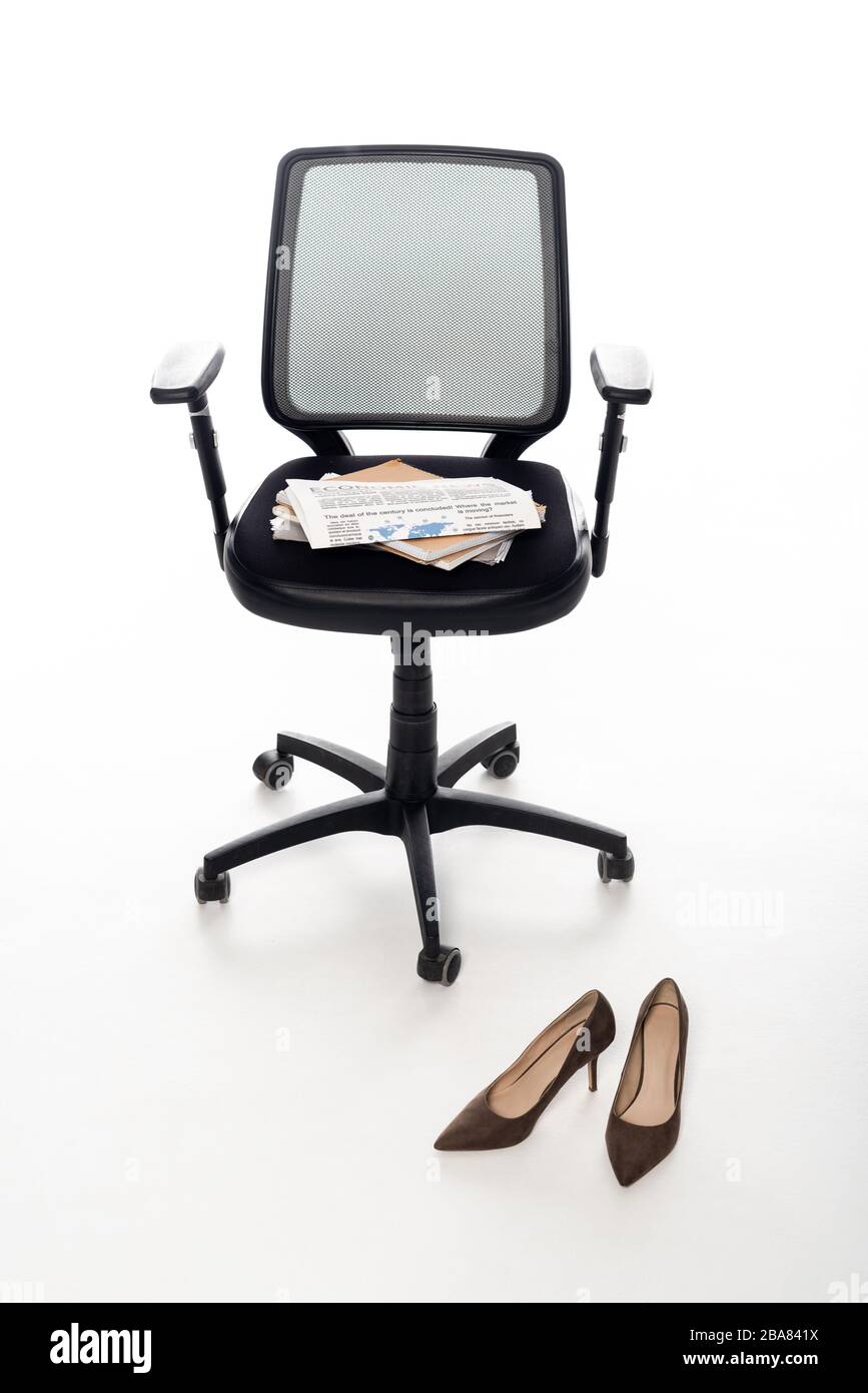 Office chair with notebooks and newspaper near shoes on white ...