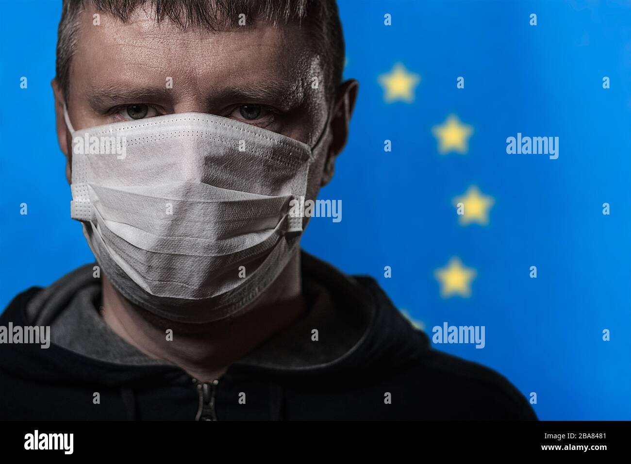 Portrait of a white man in a medical mask on the background of the flag ...