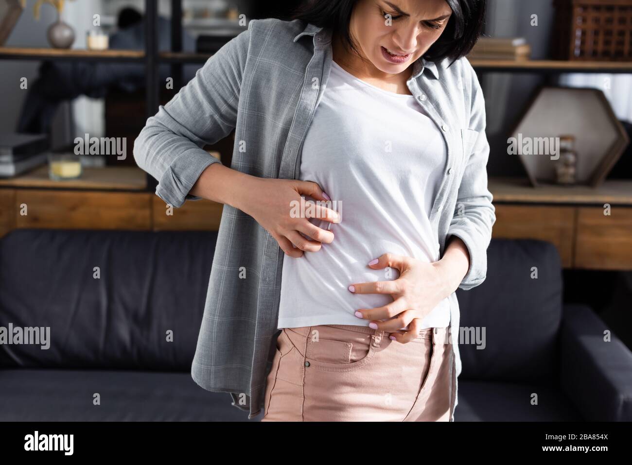 upset woman with allergy scratching stomach at home Stock Photo - Alamy