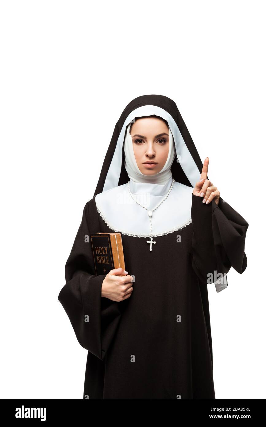 beautiful nun holding bible and pointing up with idea isolated on white ...