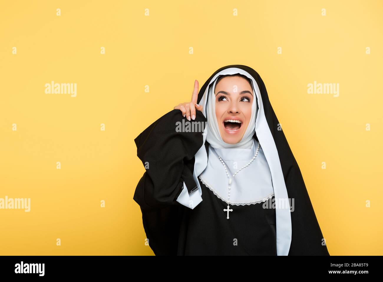 beautiful excited nun pointing up, on yellow Stock Photo - Alamy