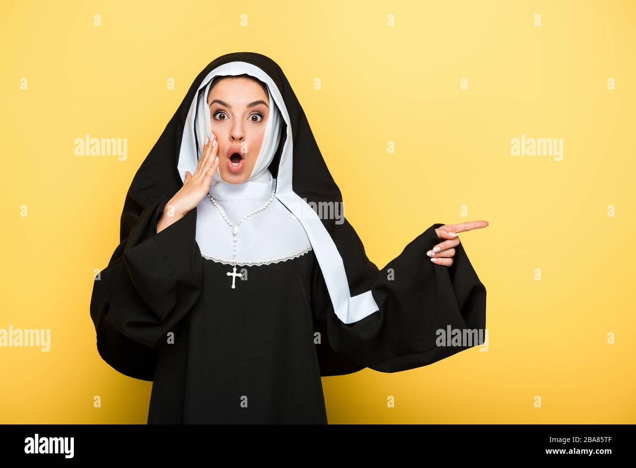 beautiful shocked nun pointing on yellow Stock Photo - Alamy