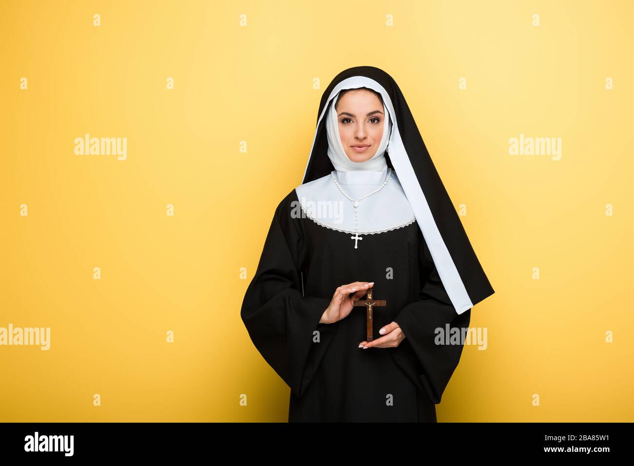beautiful happy nun holding cross on yellow Stock Photo - Alamy