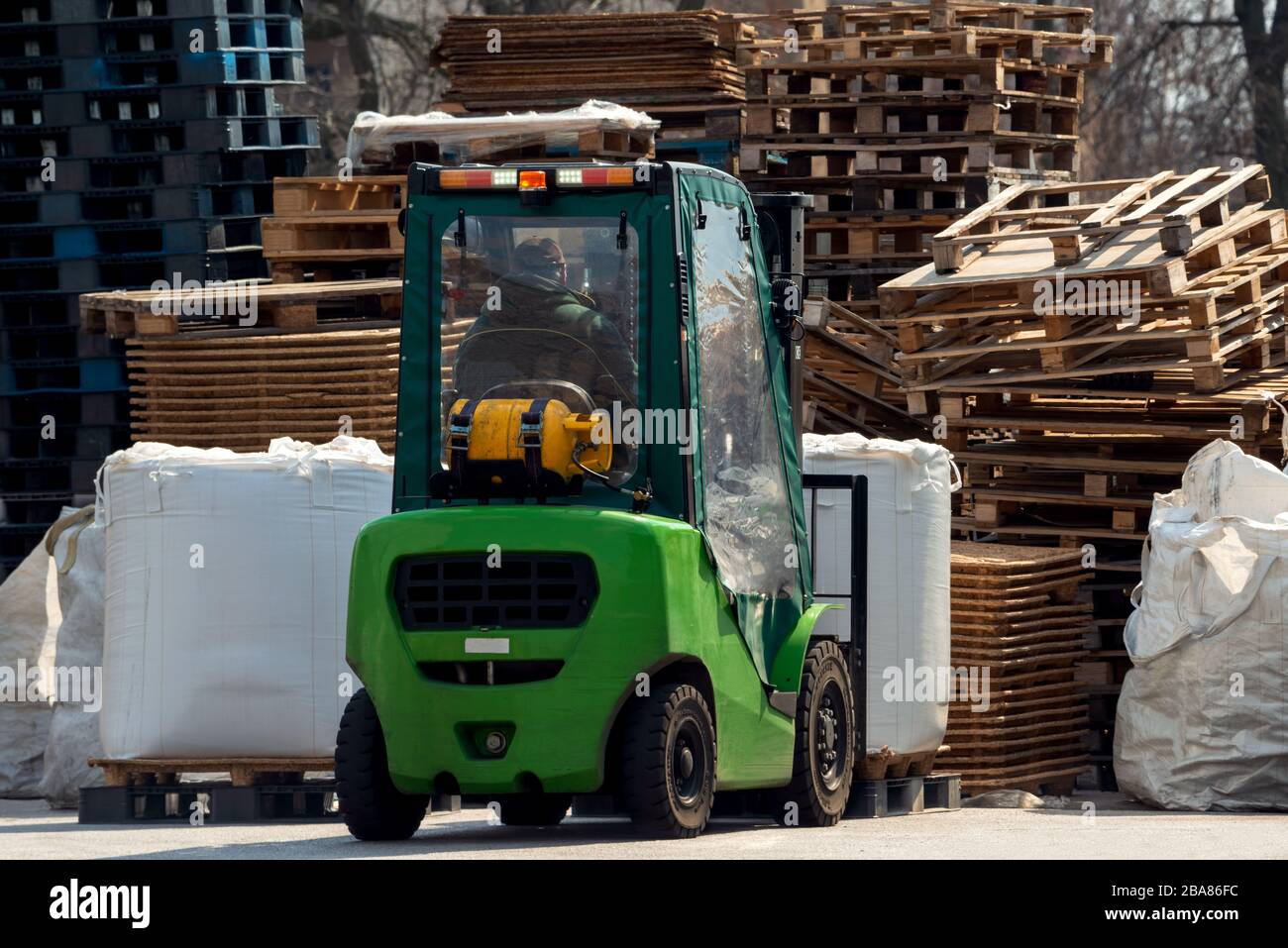 Forklift operator moves packs with goods from wooden pallets in ...