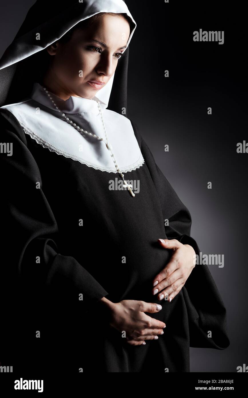 crying pregnant nun touching tummy on grey Stock Photo - Alamy