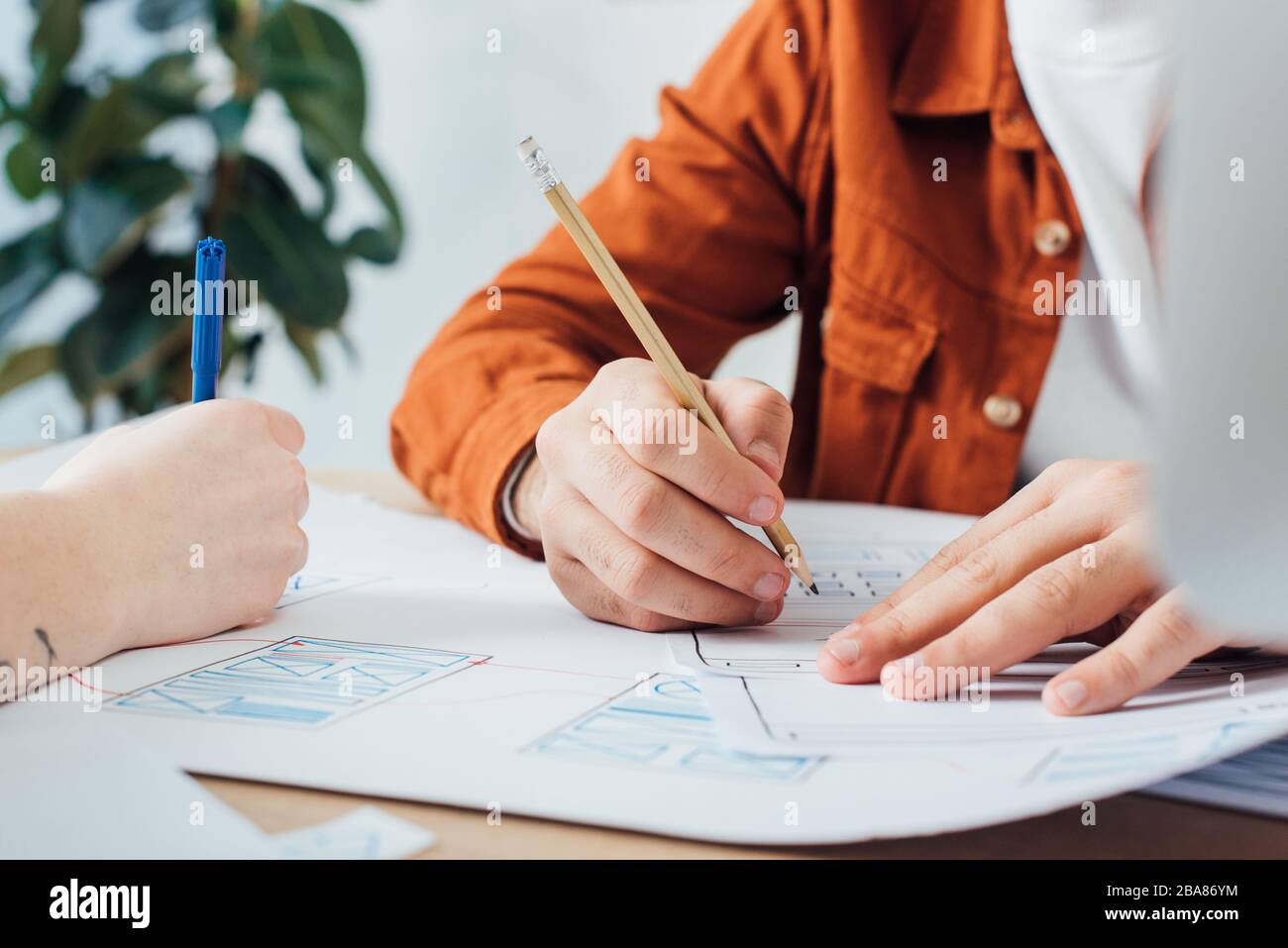 Cropped view of developers with pencil and marker working with project ...