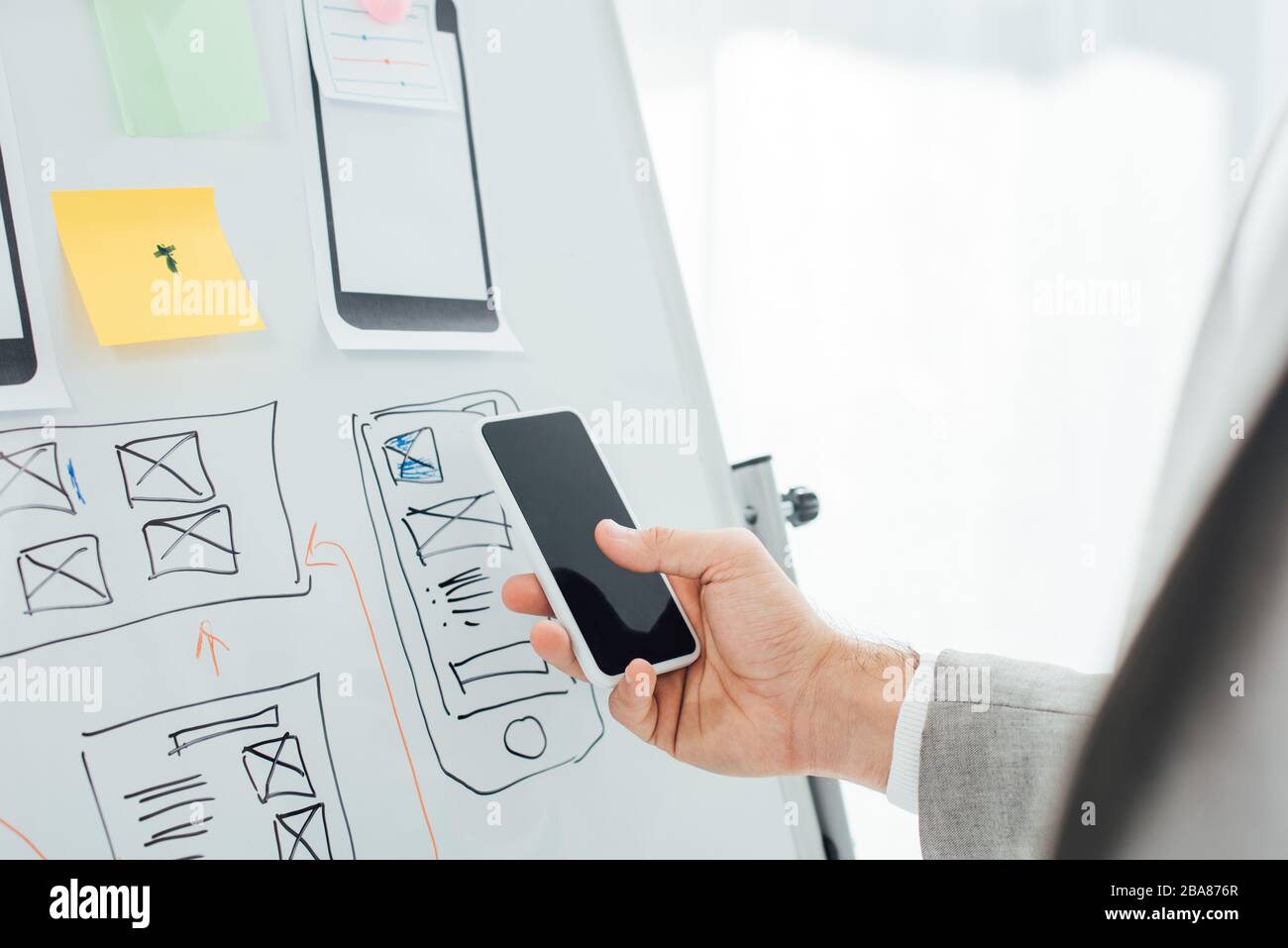 Selective focus of ux designer using smartphone near sketches and ...