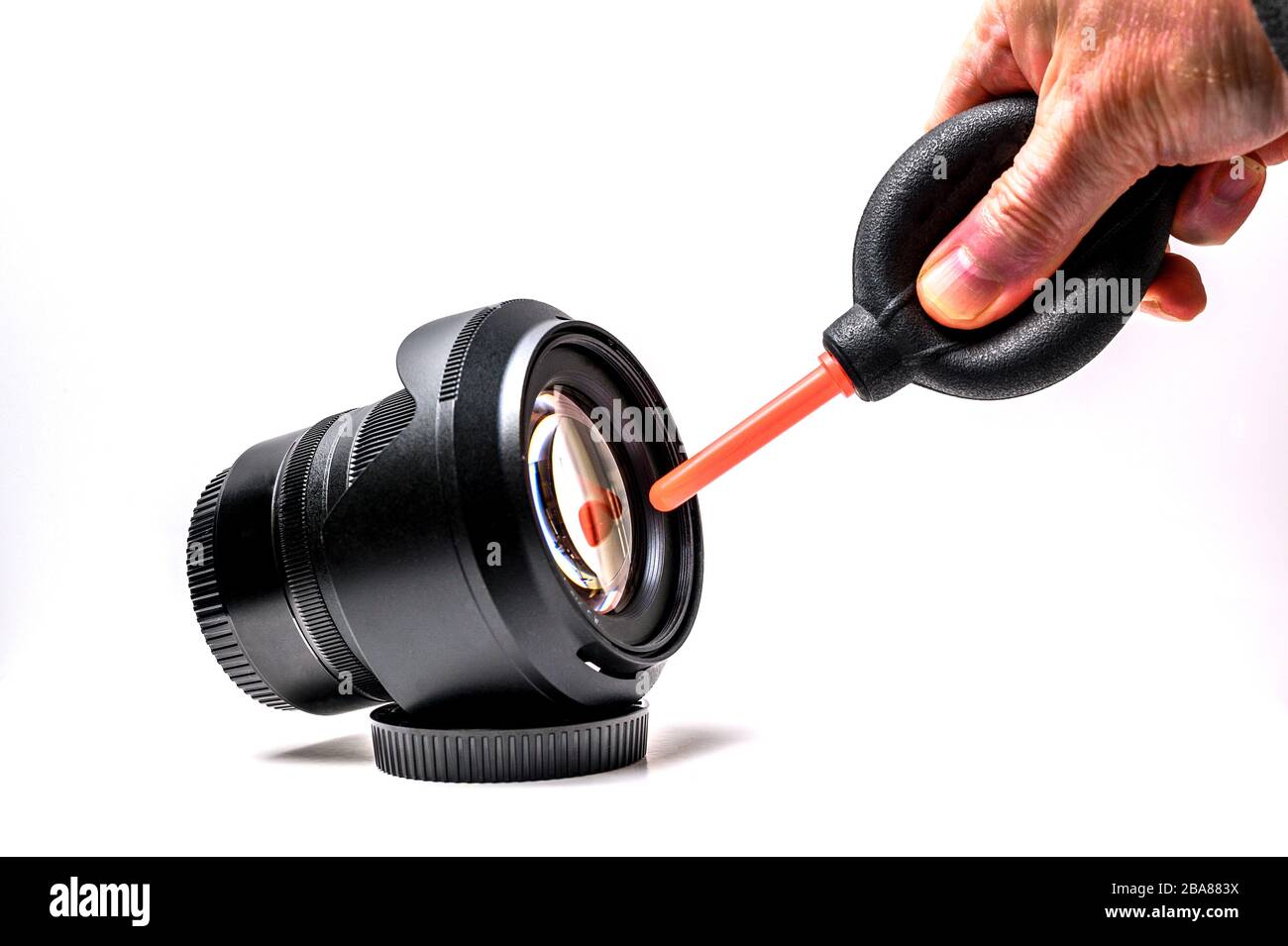 Blowing away dust and dirt from a camera lens with a rocket blower ...