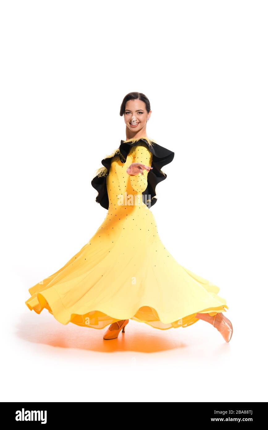 smiling elegant young ballroom dancer in yellow dress dancing on white ...