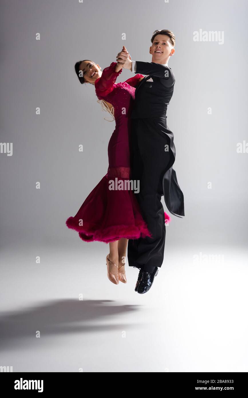 elegant young couple of ballroom dancers in red dress in suit dancing ...